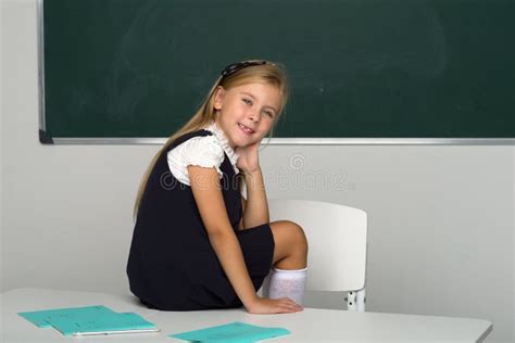 Adorable Schoolgirl Sitting On Desk In Classroom Stock Image Image Of