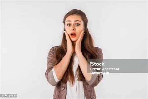 젊은 겁에 질린 여자의 초상화 놀란 겁에 질린 여성은 입에 손을 대고 대학에서 퇴학당하는 것에 충격을 받고 카메라를 보고 흰색 스튜디오 배경 위에 서 있습니다 20 24세에