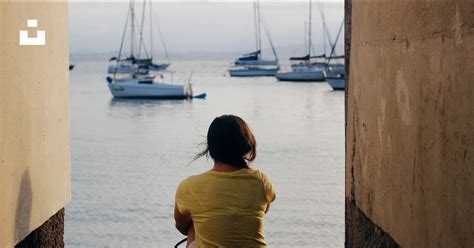 낮 동안 수역 근처의 갈색 나무 통나무에 앉아 있는 노란색 셔츠를 입은 여자 사진 Unsplash의 무료 플로리아노폴리스 Sc 이미지