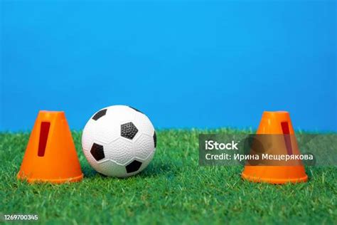 두 개의 플라스틱 콘 구속은 축구 목표를 묘사 스탠드 인공 잔디의 녹색 잔디에 그들 사이에 작은 장난감 축구 공 푸른 배경 전면 보기 닫기 스포츠에 대한 스톡 사진 및 기타