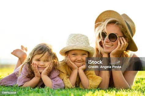 밖에서 어머니와 놀고있는 귀여운 행복한 여동생의 아름다운 사진 공원의 푸른 풀밭에 누워있는 여성과 웃는 딸들 행복한 가족 행복한 어머니의 날 가족에 대한 스톡 사진 및 기타
