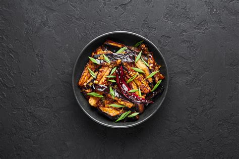 사천 가지 는 어두운 슬레이트 배경에 검은 그릇에 볶는다 가지 볶음 요리는 튀긴 가지 고추 후추 다른 소스와 중국 요리 요리입니다 공간을 복사합니다 맨 위 보기 중국 요리에