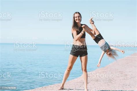 젊은 맞는 여자 엄마와 함께 해변에서 운동 하는 작은 귀여운 여자 건강 한 라이프 스타일 동적 체조 2명에 대한 스톡 사진 및 기타 이미지 Istock