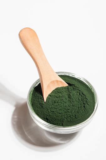 천연 첨가물과 슈퍼 푸드 녹색 스피루리나 조류 분말을 흰색 배경에 나무 숟가락으로 유리에 넣습니다 건강한 라이프 스타일 개념 유기농 식품 가루로 빻은에 대한 스톡 사진 및