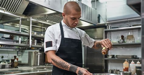 슬로우 모션 앞치마를 입고 팔에 문신을 한 잘 생긴 레스토랑 요리사가 그의 유명한 소스를 요리에 추가합니다 조리 과정 사진 Unsplash의 요리 이미지