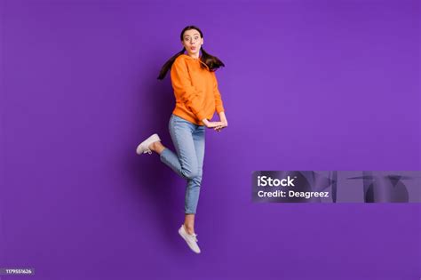 재미 펑키 한 청소년 소녀 점프의 전체 길이 사진은 보라색 보라색 색상 배경 위에 고립 된 현대 십대 옷 데님 청바지 흰색 운동화를 입고 평온한 유치한 움직이는 느낌 가을에