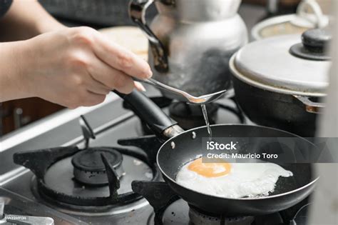 작은 프라이팬에 튀기는 계란 위에 기름을 붓기 위해 숟가락을 들고 있는 소녀의 손을 자세히 보여줍니다 20 24세에 대한 스톡 사진 및 기타 이미지 Istock