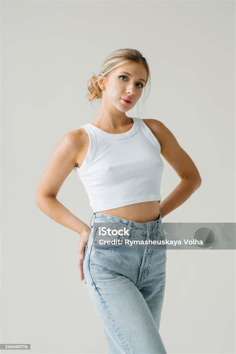 Caucasian Woman Is Wearing A White Top And Blue Jeans She Stands