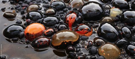 Crude Oil Spills Mix With Seawater On Beach Stones Creating A Stark Contrast Between The Dark
