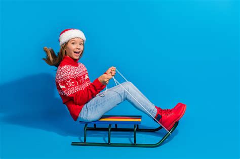 기쁨 흥분 십대 소녀 착용 점퍼 산타 모자의 전체 길이 사진 썰매를 타고 파란색 배경에 고립 된 빈 공간에 간다 크리스마스에 대한 스톡 사진 및 기타 이미지 Istock