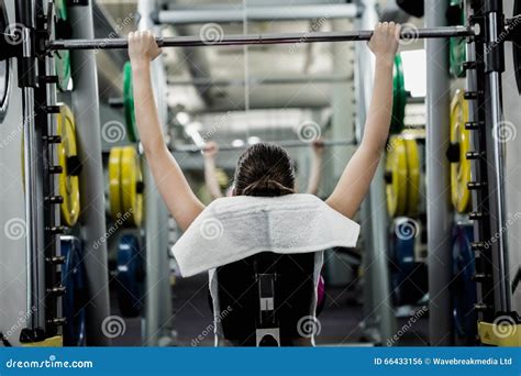 Подходящая женщина поднимая жим лёжа штанги Стоковое Фото изображение