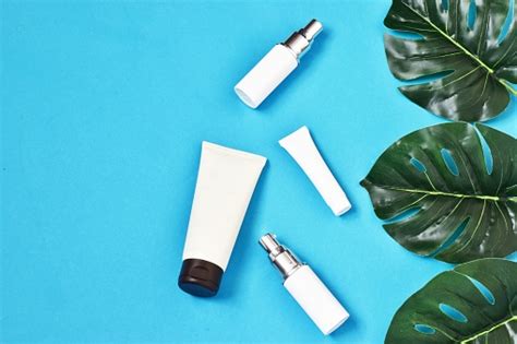 포메라 잎이 있는 파란색 배경의 화이트 스킨 케어 화장품 병 바이오 뷰티 제품 포장 디자인 광고 화장품 제품 플랫 레이 상단 보기 컨셉 뷰티 공간을 복사합니다 0명에 대한