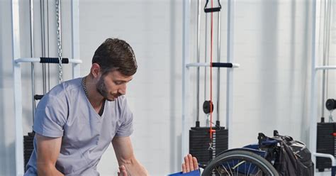 남성 물리 치료사는 근력 재활 운동을 위해 매트에 누워있는 동안 탄성 밴드를 잡고 있습니다 사진 Unsplash의 환자 이미지