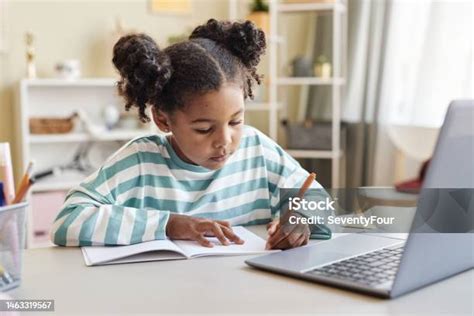 집 안의 책상에서 숙제를 하는 노트북에 글을 쓰는 귀여운 흑인 소녀 가정 생활에 대한 스톡 사진 및 기타 이미지 가정 생활 개발 곱슬 머리 Istock