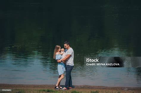 아기 딸을 가진 부모는 호숫가의 물 위에 서서 포옹합니다 3 명에 대한 스톡 사진 및 기타 이미지 3 명 가족 강