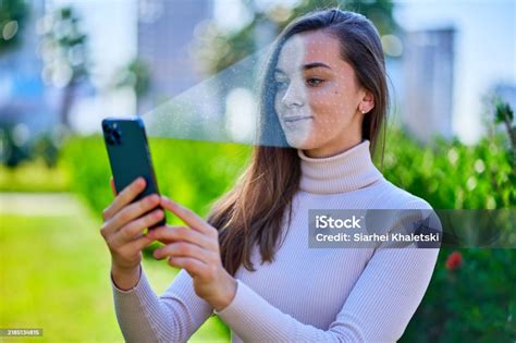 Modern Woman Scans Face Using Facial Recognition System On New Smartphone For Biometric