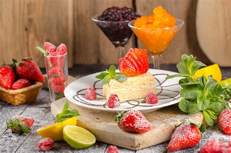 접시에 나폴레옹 달콤한 케이크 오래 된 나무 슬라이스 빈티지 소박한 보드 잼 가루 설탕 신선한 민트 딸기와 라스베리 라임 및 레몬 사탕수수 설탕 사과 신선한 면에 누워 제거