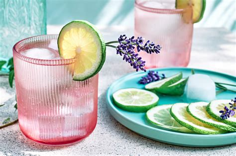 파스텔 라이트 블루 배경 근처의 테이블에 라임 슬라이스와 라벤더 꽃이 들어간 시원한 라벤더 레모네이드 건강한 유기농 여름 소다 음료 해독 물 다이어트 Unalcolic