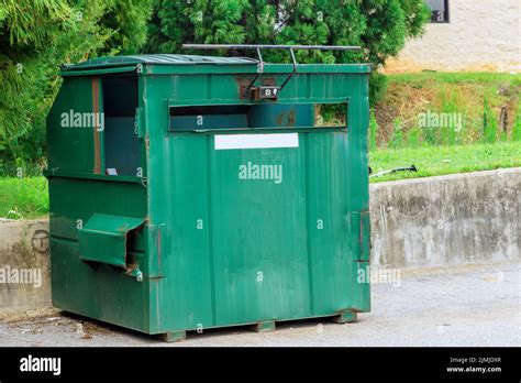 There Is A Garbage Container Bin Near An Apartment Building Where