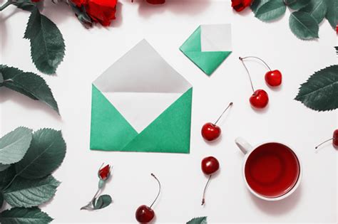 홍차 익은 체리 흰색 바탕에 녹색 잎 장미 누워 있는 작은 봉투 작업 하는 동안 마시는 차 음료를 치유 향기로운 아침입니다 베리 설탕에 절인 과일입니다 평면 위치 최고 볼