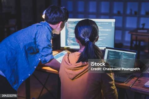두 명의 젊은 남녀 프로그래머가 밤늦게 따뜻하고 시원한 조명이 있는 사무실에서 함께 코딩 작업을 하고 있습니다 어두운 색에 대한 스톡 사진 및 기타 이미지 Istock