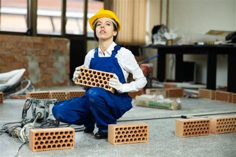 Female Builder In Safety Hard Hat Preparing Bricks For Erection Of Partition Wall Stock Photo