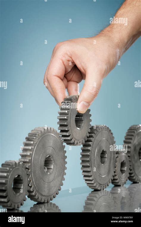 Man Adding A Cog Gear Wheel Into A Row Of Old Cogs Stock Photo Alamy