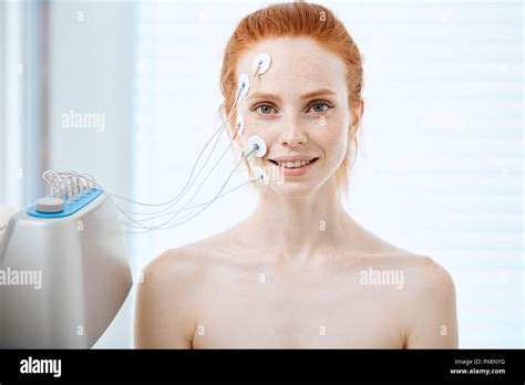 Young Woman With Electrodes On Her Face Receiving Electric Stimulation