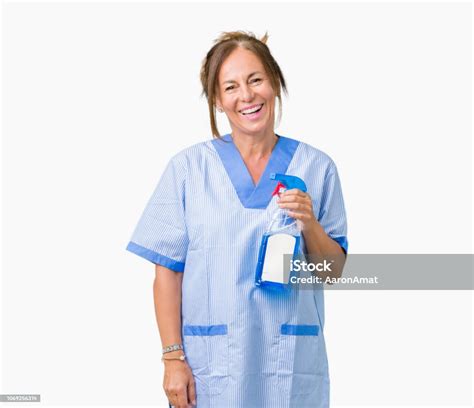 중간 나이 갈색 머리 청소기 여자 서 치아를 보여주는 자신감 미소로 웃 고 행복 한 얼굴로 고립 된 배경 위에 가사 유니폼을 입고 가사 집안일에 대한 스톡 사진 및 기타