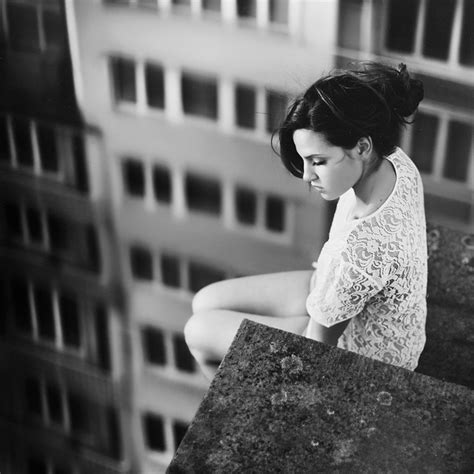 Фото Девушка сидит на краю крыши дома