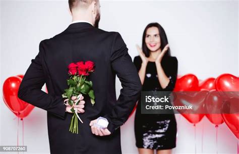 발렌타인의 하루입니다 검은 양복에 남자는 그의 아름 다운 사랑 하는 여자에 대 한 그의 뒤 장미 꽃다발을 들고 있다 결혼식에 대한 스톡 사진 및 기타 이미지 Istock