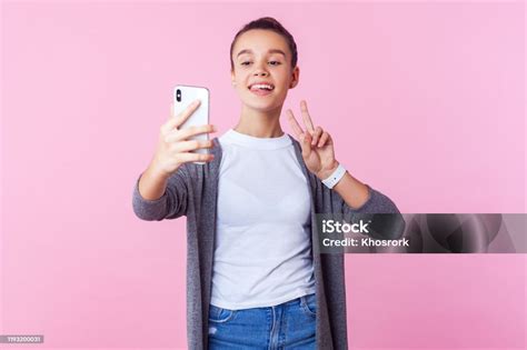 롤빵 헤어 스타일 승리 기호와 비디오 통화를하는 동안 혀를 보여주는 쾌활한 미친 십대 소녀의 초상화 분홍색 배경 화상 통화에 대한 스톡 사진 및 기타 이미지 Istock