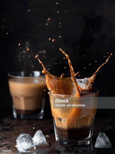 어두운 배경에 아이스 커피와 함께 유리에 스플래시 얼음 조각을 곁들인 상쾌한 아이스 카푸치노 음료 차가운 음료의 물결 닫기 세로