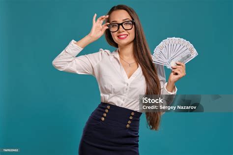 검은 색 짧은 치마와 흰색 블라우스를 입고 안경을 쓴 갈색 머리 소녀가 파란색 배경에 대해 백 달러 지폐의 팬을 들고 포즈를