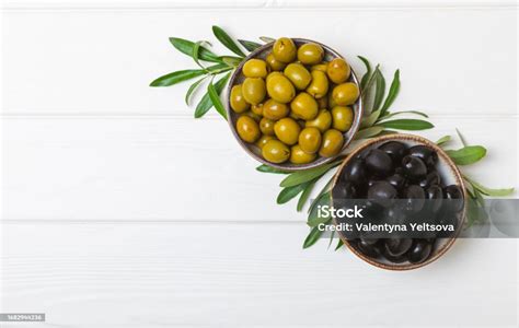녹색과 검은색 올리브는 질감이 있는 오래된 나무 배경에 그릇에 나뭇잎이 있습니다 맛있고 건강한 음식 진미지중해식 주방 텍스트를 위한 위치입니다 카피스페이스 건강한 생활방식에