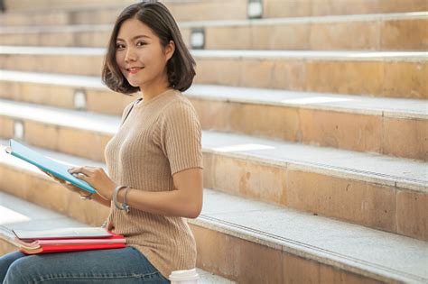 그녀의 책과 계단 고등학교 프로그램 스마트 십 대 개념을 학습 하는 사람들이 교육에 앉아 커피 한 잔을 들고 아름 다운 아시아 여성 대학 학생 공부에 대한 스톡 사진 및