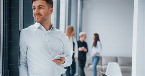 사무실에서 실내에서 함께 일하고 의사 소통하는 젊은 성공적인 팀 앞에서 전화기를 손에 들고 서 있는 정장을 입은 남자 사진 Unsplash의 우크라이나 이미지