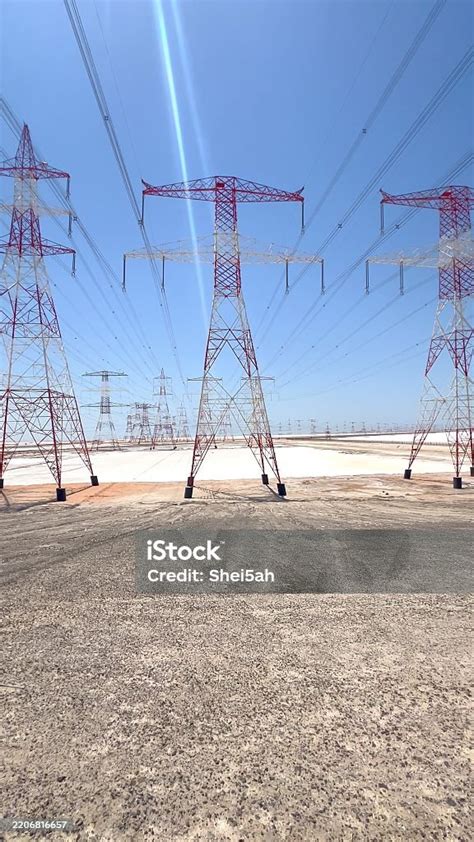 송전선을 운반하는 높은 금속 타워는 사막의 모래를 가로질러 뻗어 있으며 푸른 하늘을 배경으로 뚜렷하게 서 있는 건축물은 사막 공학 및 전력망은 현대 기술의 건조한 생태를