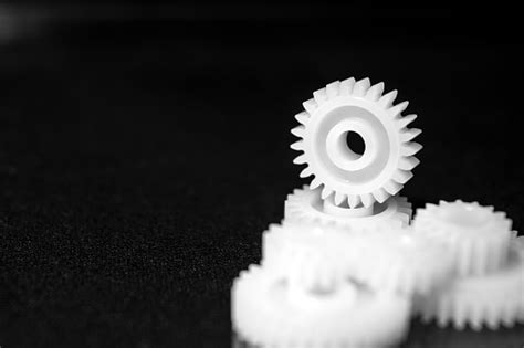 검은 거울 배경에 여러 흰색 플라스틱 기어 기계적 수리 수정 반사 수리 점 톱니바퀴 큰 메커니즘의 요소입니다 조화로운 작업 흐린