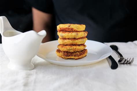 사워 크림 소스와 흰색 그레이비 보트 접시에 커드 치즈 팬케이크 포크 흰색 일반 식탁보에 칼을 서있는 테이블과 검은 색 티셔츠에