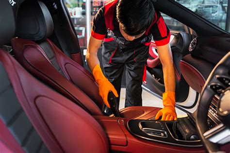 세차장 직원이 진공 청소기로 청소하고 차를 청소하고 실내 장식품을 청소하고 자동차 콘솔을 청소합니다 초점이 맞춰진 클로즈업 촬영 이미지의 부분적인 선명도 세차장에 대한 스톡