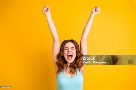 물결 모양의 곱슬 곱슬 거리는 사진 은 노란색 배경으로 고립 된 동안 청록색 싱글을 입고 얼굴로 그녀의 기뻐를 표현하는 예쁜 귀여운 여자 친구를 찡그리다 공휴일에 대한 스톡