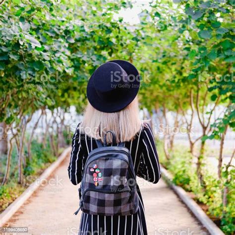 녹색 정원에서 골목을 따라 걷는 배낭검은 모자를 쓴 금발 소녀 여성 솔로 여행 개념입니다 거리에 대한 스톡 사진 및 기타 이미지 Istock
