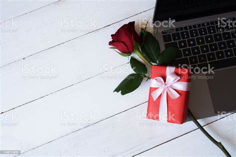 빨간 장미와 빨간 선물 상자와 흰색 나무 배경에 노트북이 있습니다 발렌타인 데이 결혼식 생일 및 특별한 날 개념 텍스트 공간을 복사합니다 평면도 플랫 레이 2월에 대한 스톡