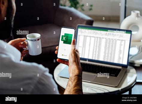 Man Using A Mobile Phone Displaying Logo Of Microsoft Excel On The Screen Spreadsheet Software