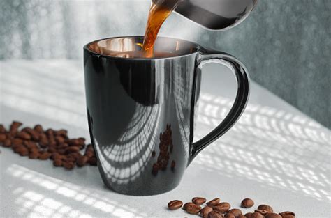 컵에 세즈브에서 뜨거운 커피를 붓고 증기가 상승합니다 창가와 흩어진 커피 콩의 오픈워크 그림자의 배경에 대하여 0명에 대한 스톡 사진 및 기타 이미지 Istock