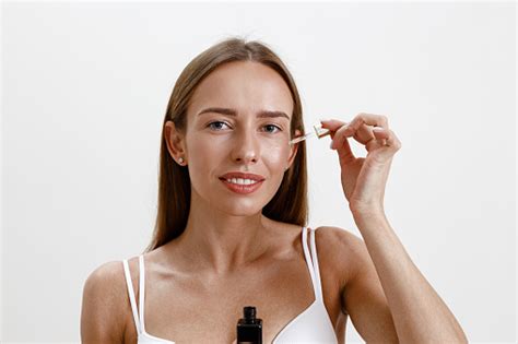 여자는 그녀의 얼굴에 화장품 보습 세럼 또는 오일 스튜디오 배경에 얼굴 에센스를 적용 25 29세에 대한 스톡 사진 및 기타 이미지 25 29세 갈색 갈색 머리