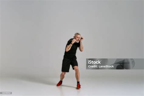 회색 배경을 통해 스튜디오에서 운동하는 동안 검은 색 스포츠웨어 연습 펀치에 중년 근육 남자의 전체 길이 샷 운동에 대한 스톡 사진 및 기타 이미지 Istock