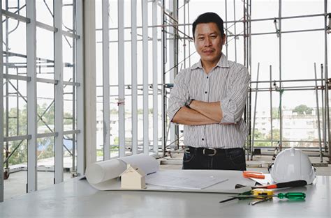 프로젝트 계약자 및 엔지니어링 개념을 시작 인사말 건설 현장 건물에서 회의 테이블에 건설 도구와 스마트 엔지니어 건축가 또는 기술자 교차 팔 개발에 대한 스톡 사진 및 기타