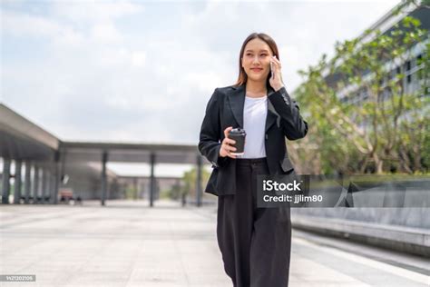 아름다운 젊은 아시아 여성 사무실 임원 여성이 스마트 폰을 걷고 사용하고 사무실 건물 밖에서 커피 한 잔을 마시고 있습니다 25 29세에 대한 스톡 사진 및 기타 이미지